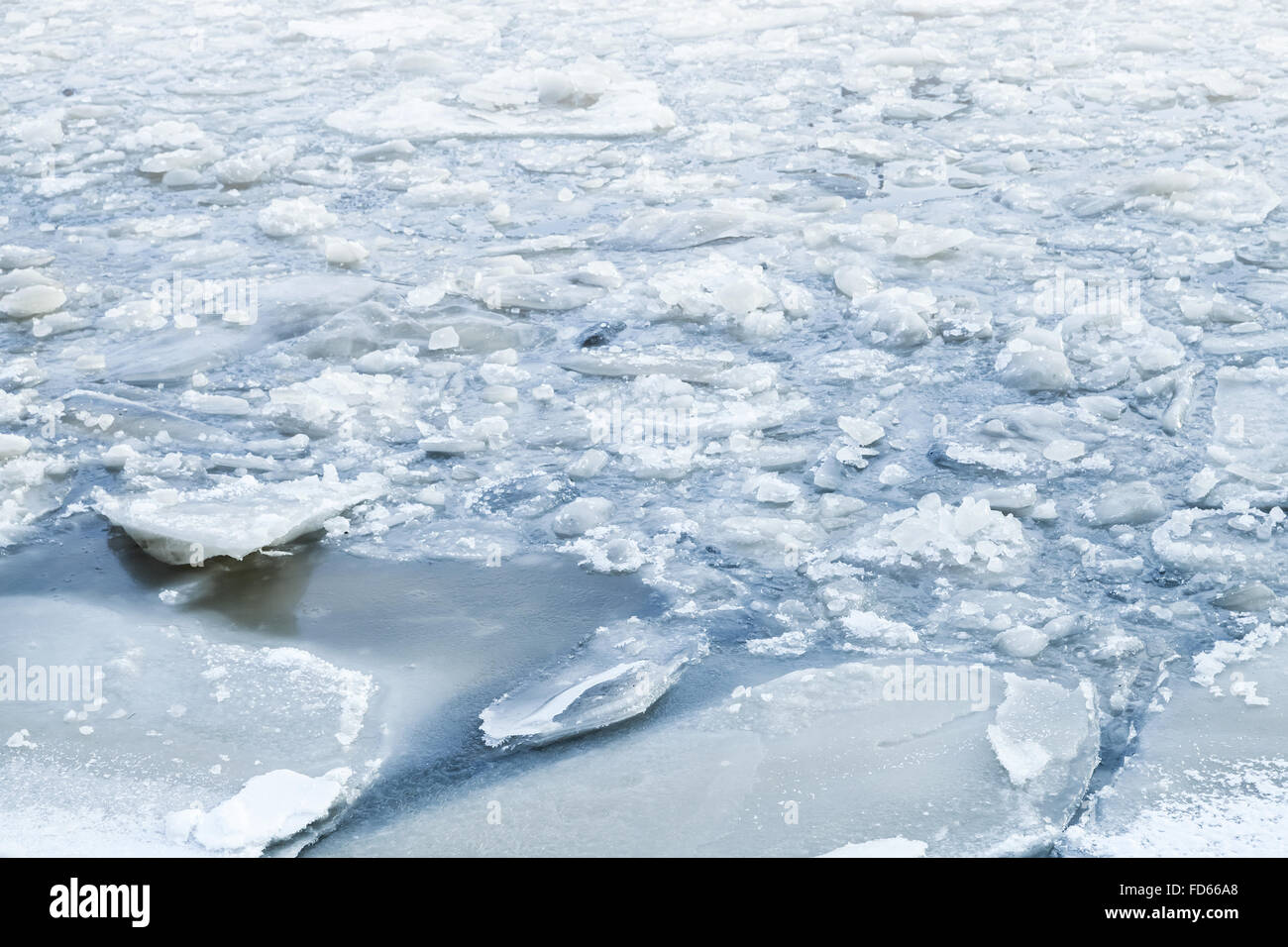 Ice fragments covered with show on cold river water. Dark blue natural ...