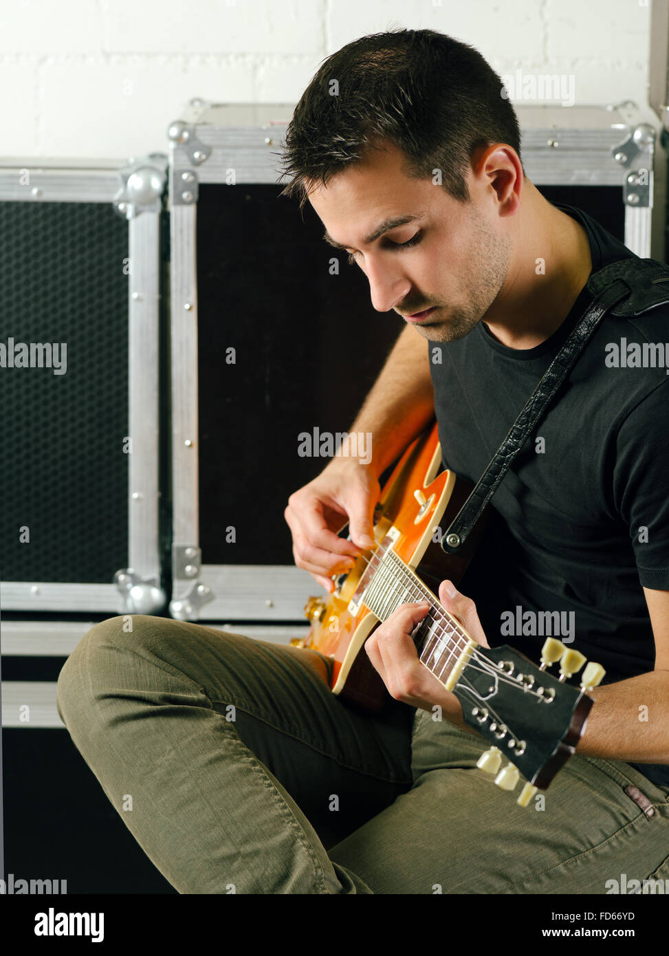 Photo of a man sitting backstage practicing his guitar Stock Photo - Alamy