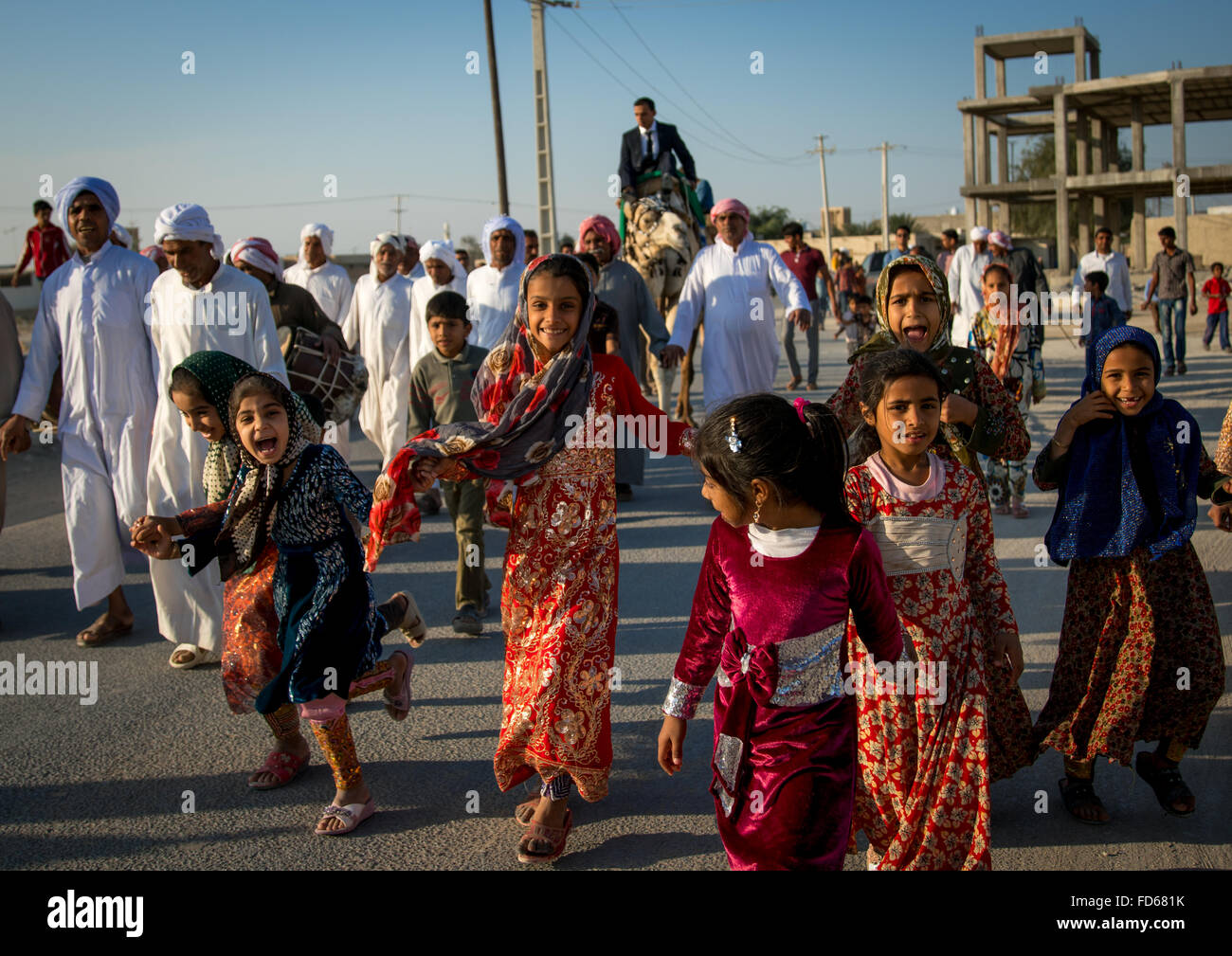girls running in front of a groom riding his camel during the wedding ...