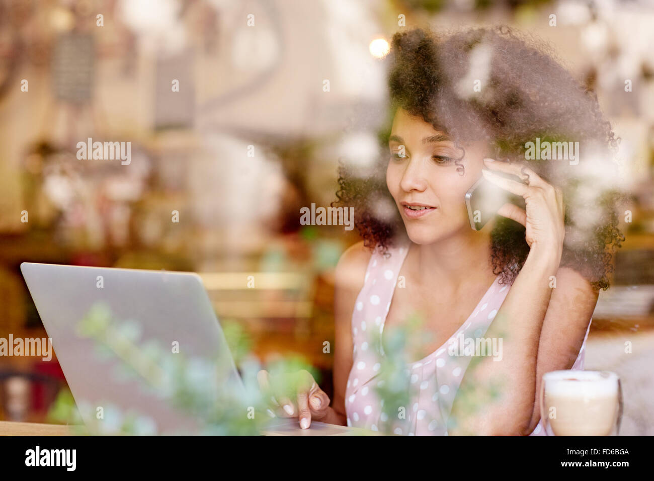 Woman typing her laptop and talking on phone Stock Photo - Alamy