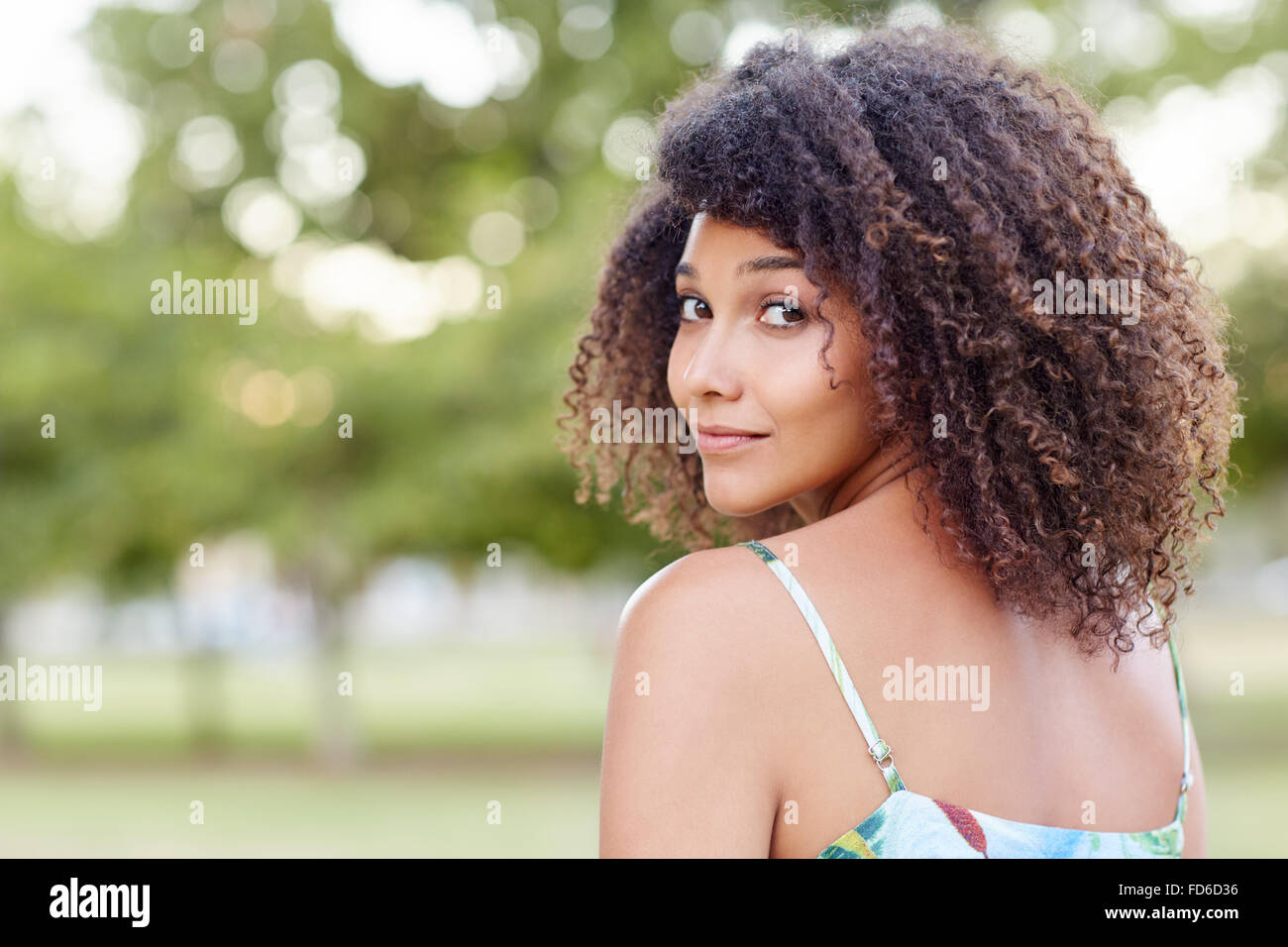 Young woman looking back over her shoulder in a park Stock Photo - Alamy