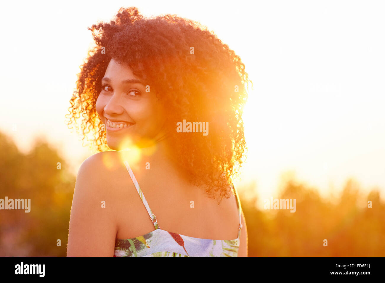 Woman looking back over her shoulder with sun flare Stock Photo - Alamy