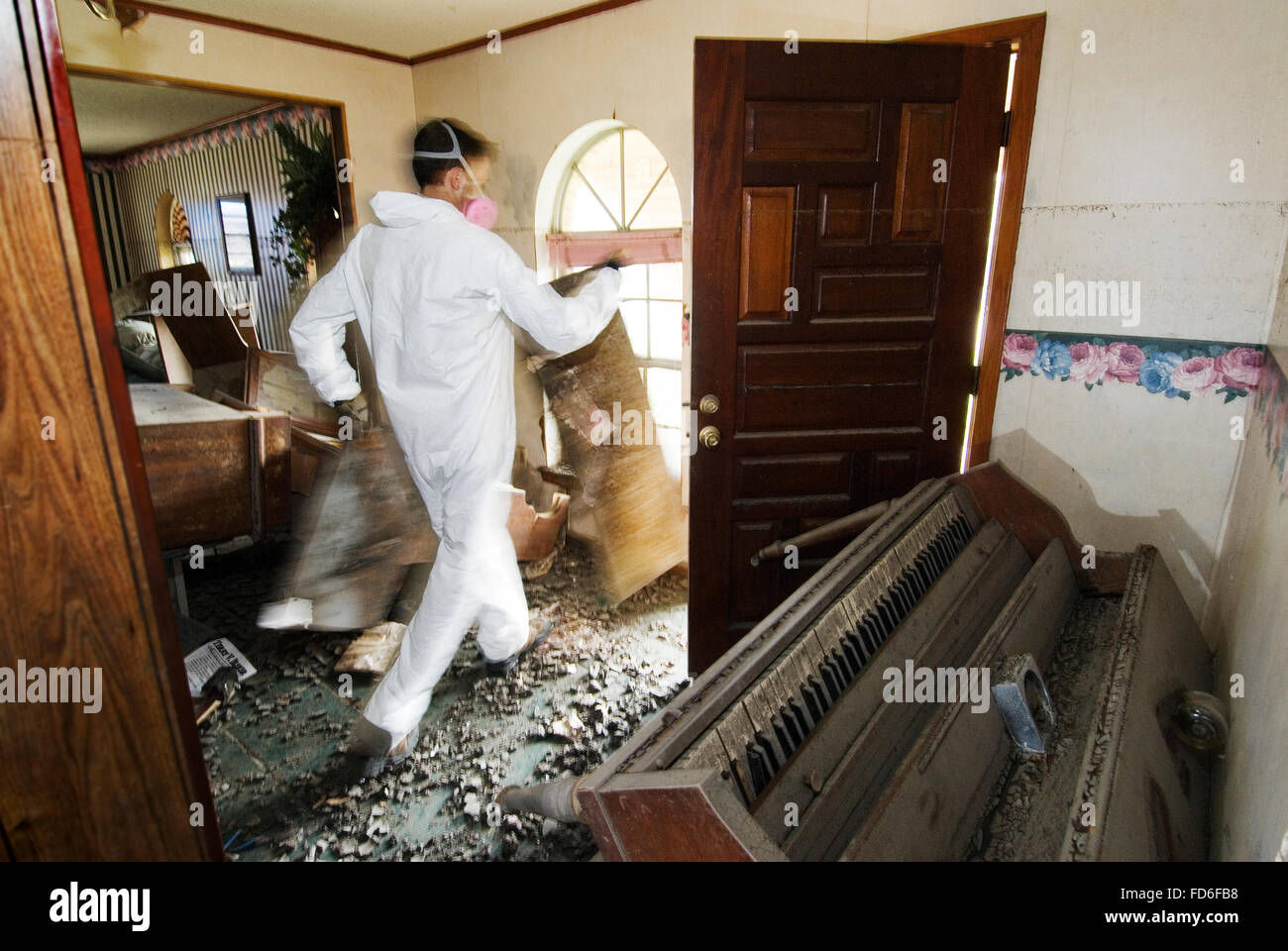 Volunteers in full protective gear strip heavily molded drywall and ...