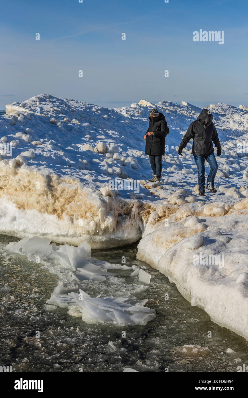 Hikers at icy edge of Lake Michigan in winter, Rosy Mound Natural Area ...