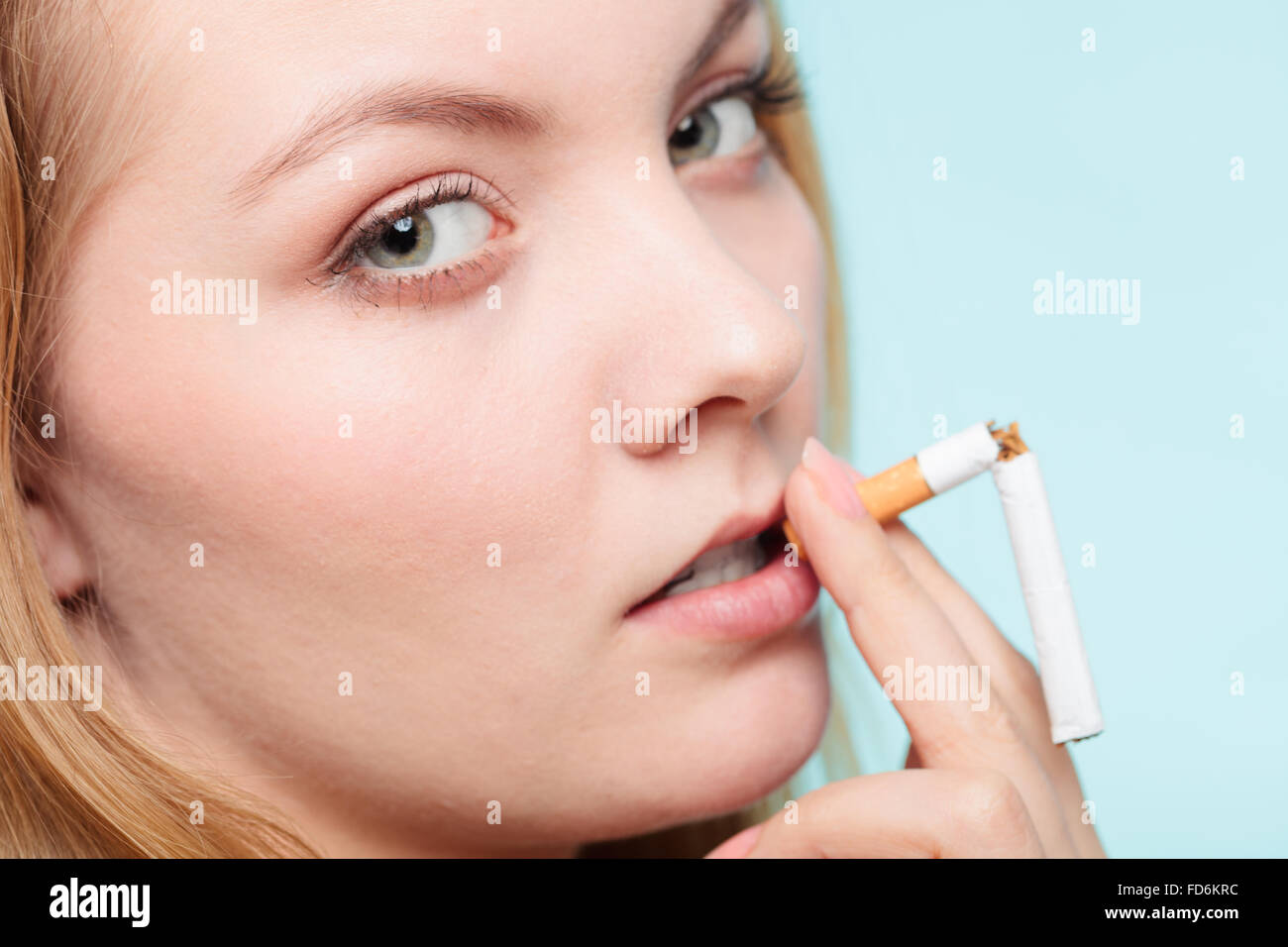 Smilling pretty girl smoking breaked down cigarette. Winning with ...