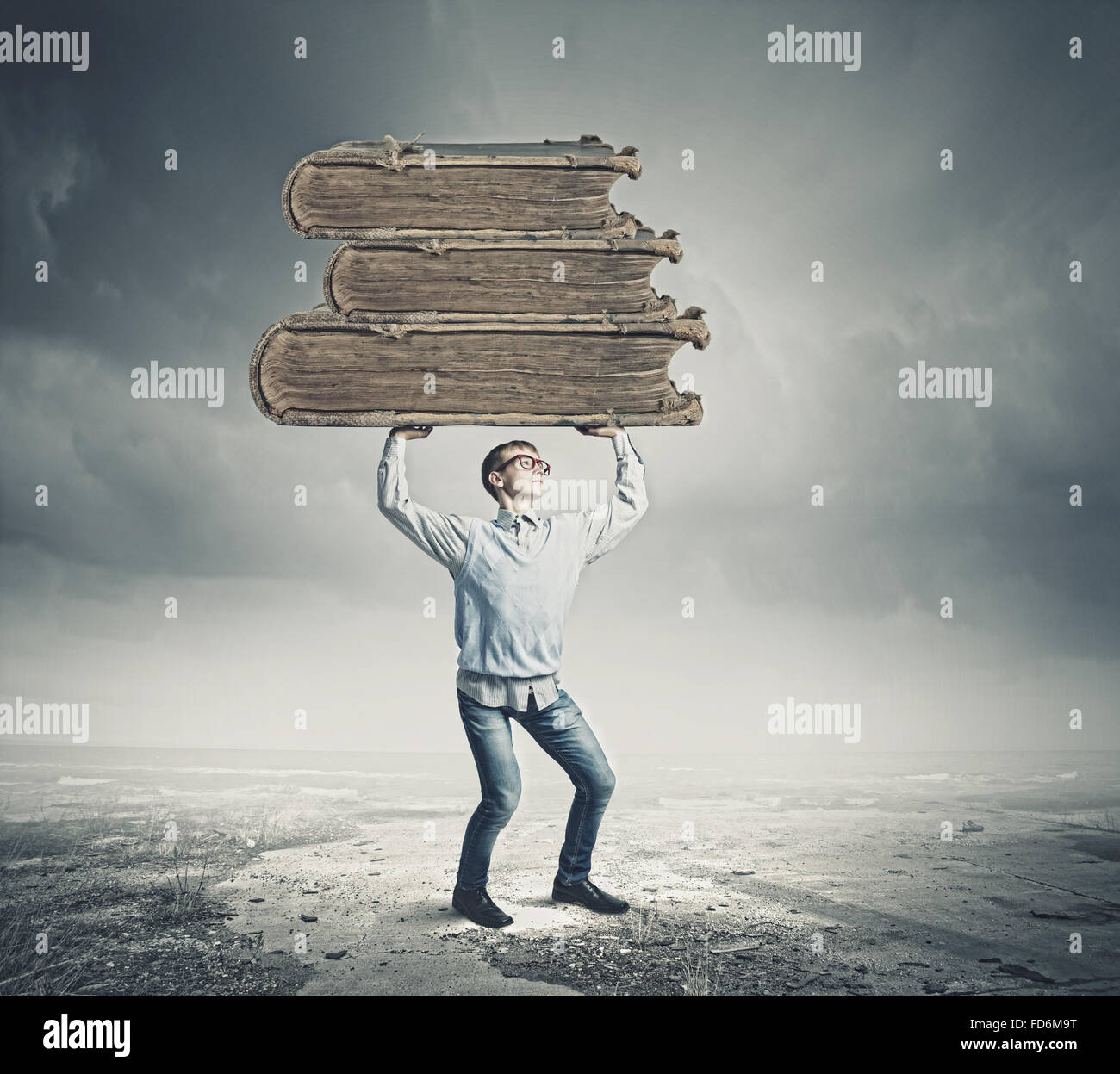Young man holding huge book above head Stock Photo - Alamy