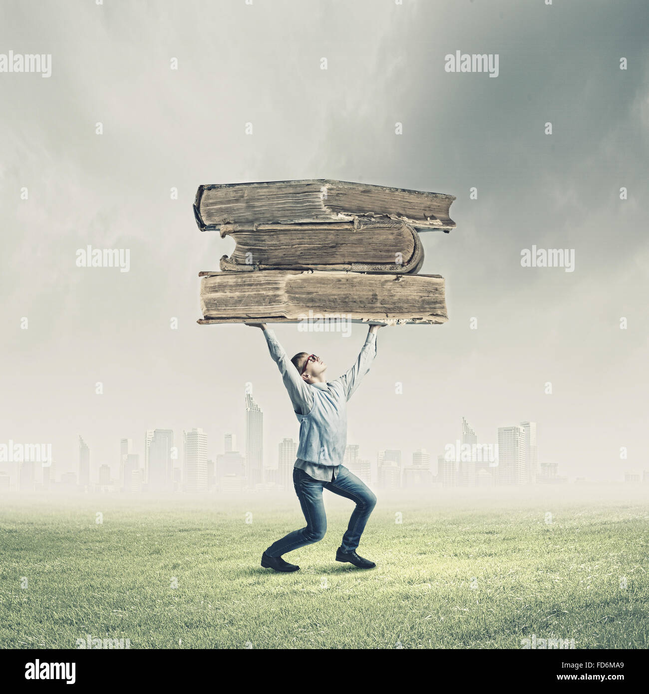 Young man holding huge book above head Stock Photo - Alamy