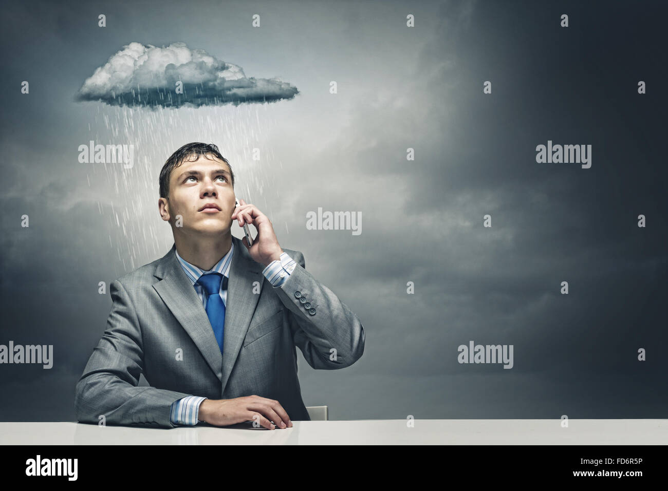 Businessman sitting under rain talking on mobile phone Stock Photo - Alamy