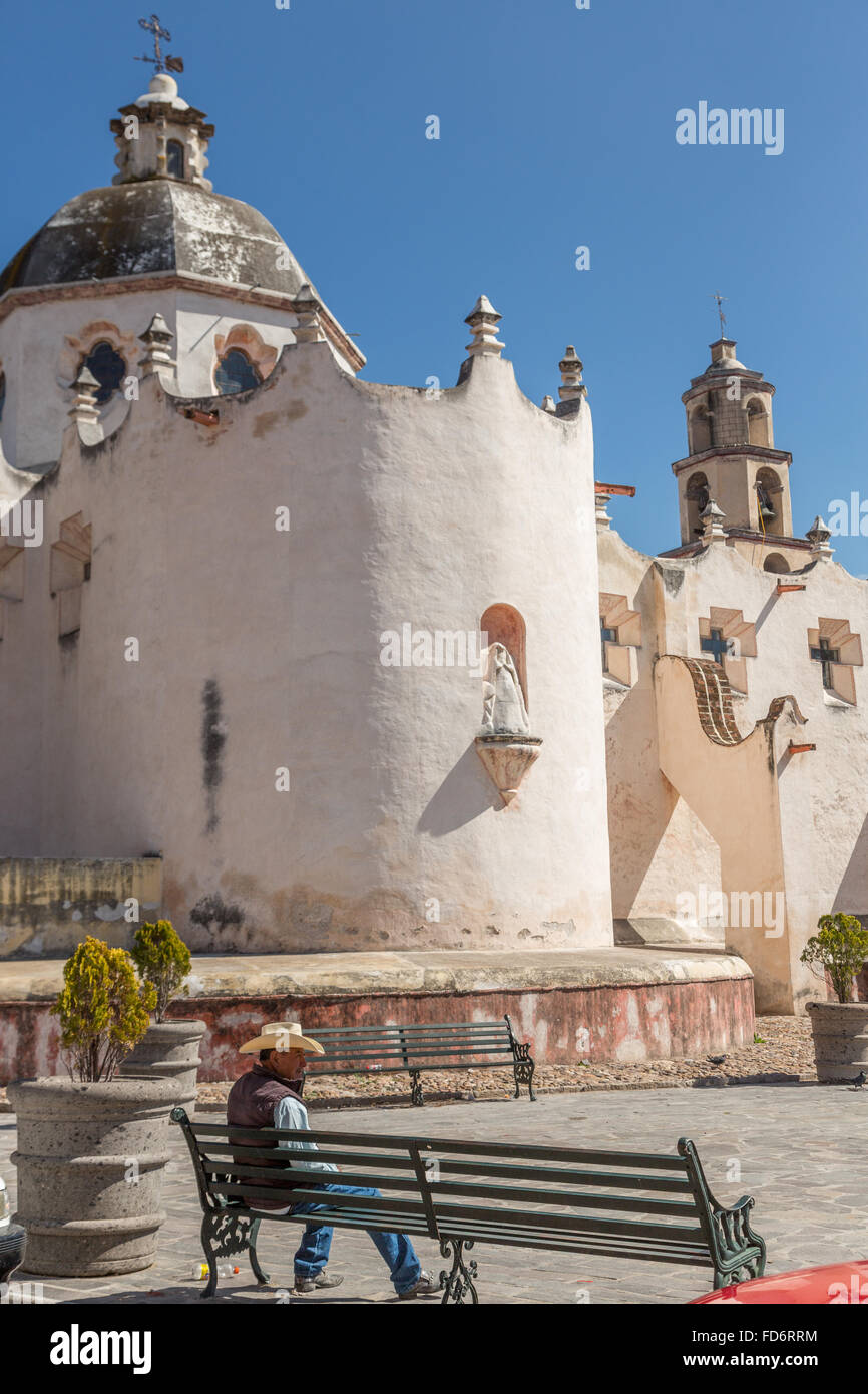 A Mexican pilgrim rests outside the fortress like Mexican baroque Sanctuary of Atotonilco and ...