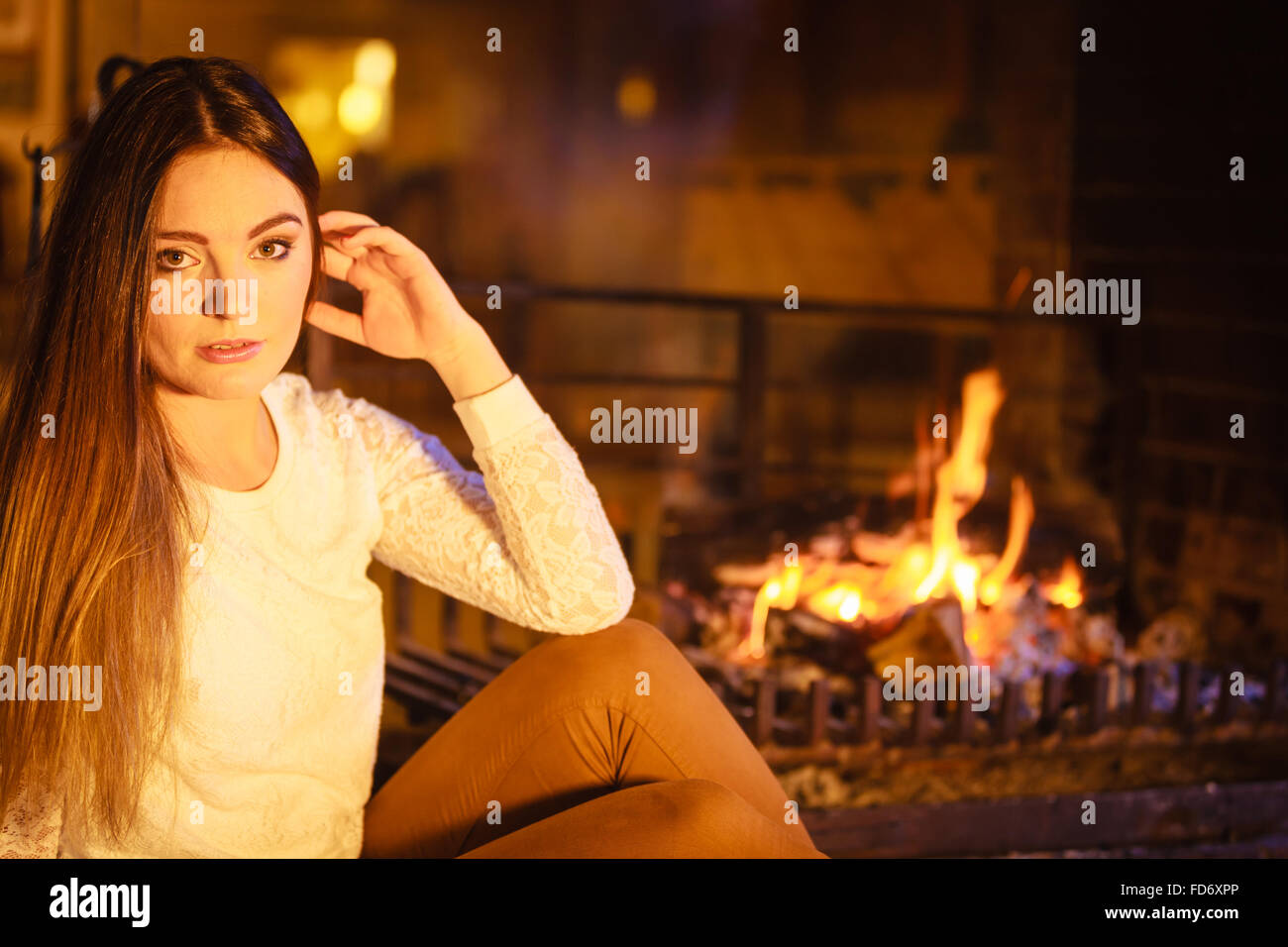 Woman relaxing resting at fireplace. Young girl heating warming up ...