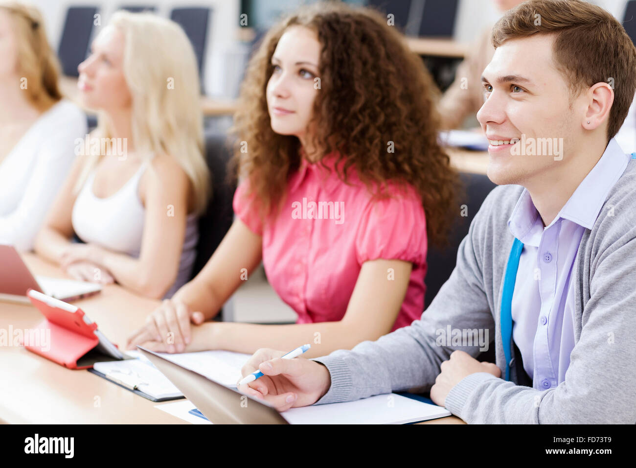 Young people sitting in classroom at lesson Stock Photo - Alamy