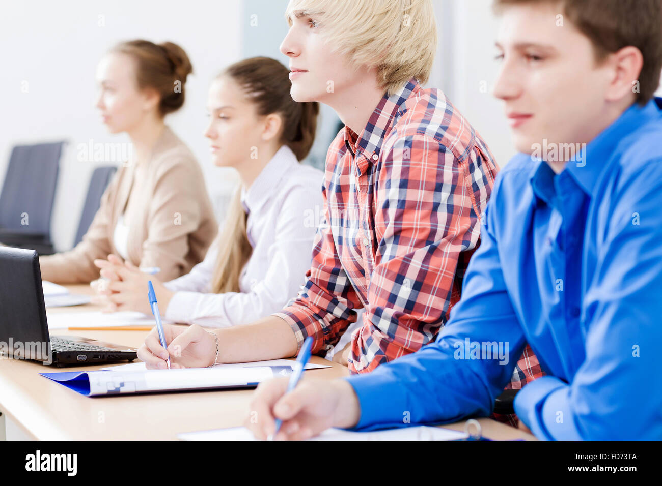 Young people sitting in classroom at lesson Stock Photo - Alamy
