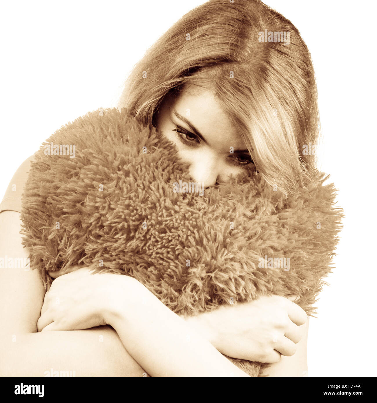 Woman blonde sad unhappy girl hugging heart shaped big pillow studio ...