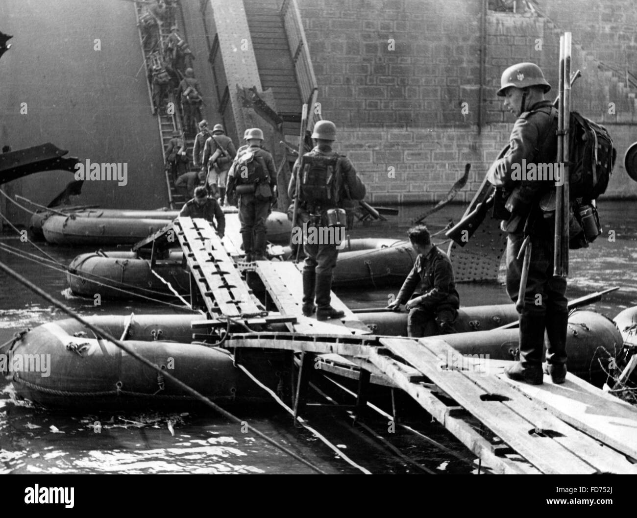 German soldiers crossing a bridge destroyed by the Dutch near ...