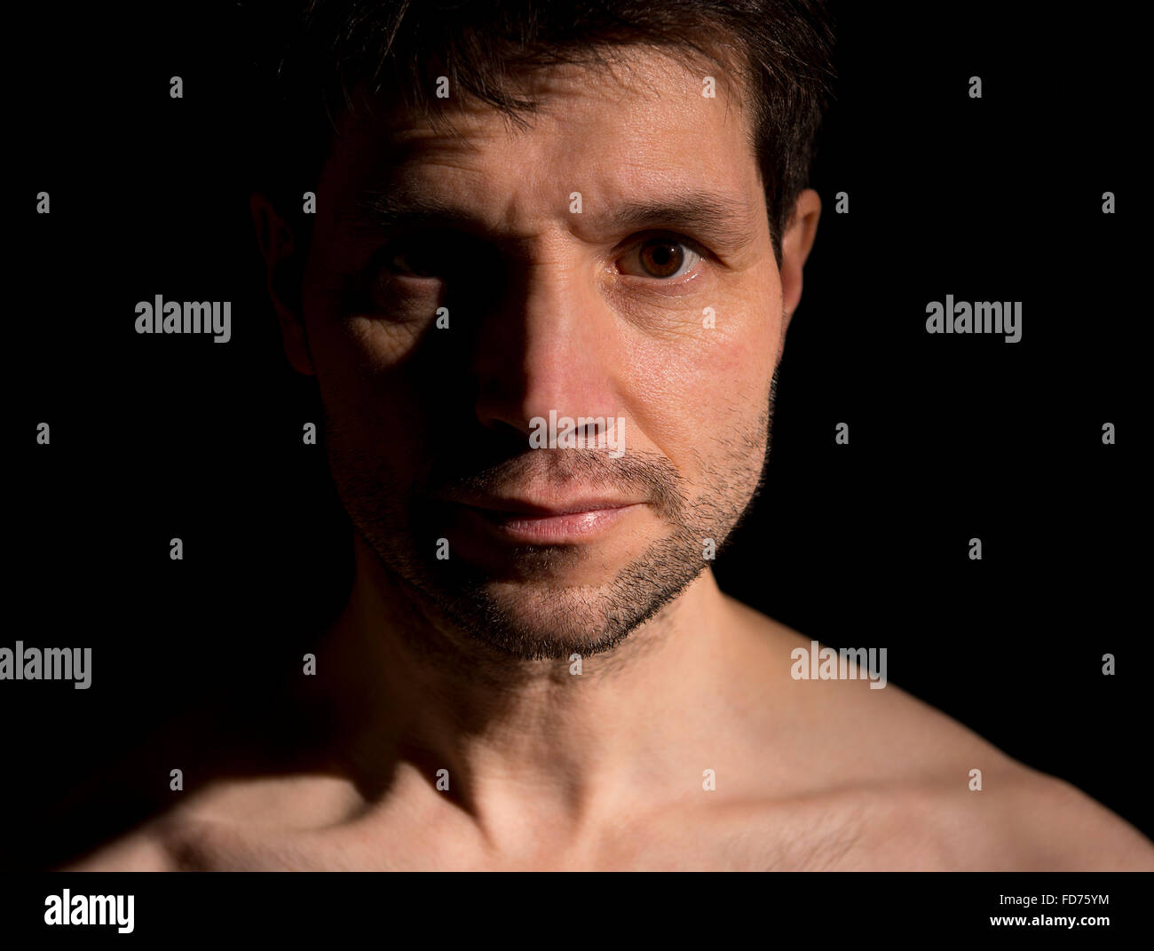 Head and shoulders portrait, of shirtless man with half his face in ...