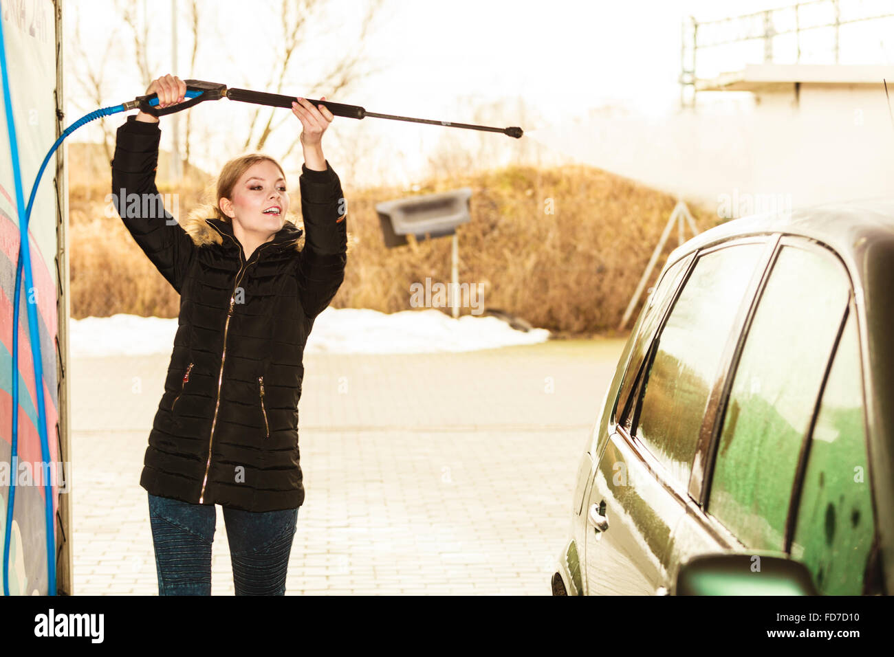 Manual auto wash. Young attractive blonde woman washing the dirty car ...