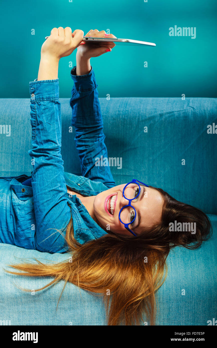 Happy young woman girl in glasses laying on sofa couch using computer ...