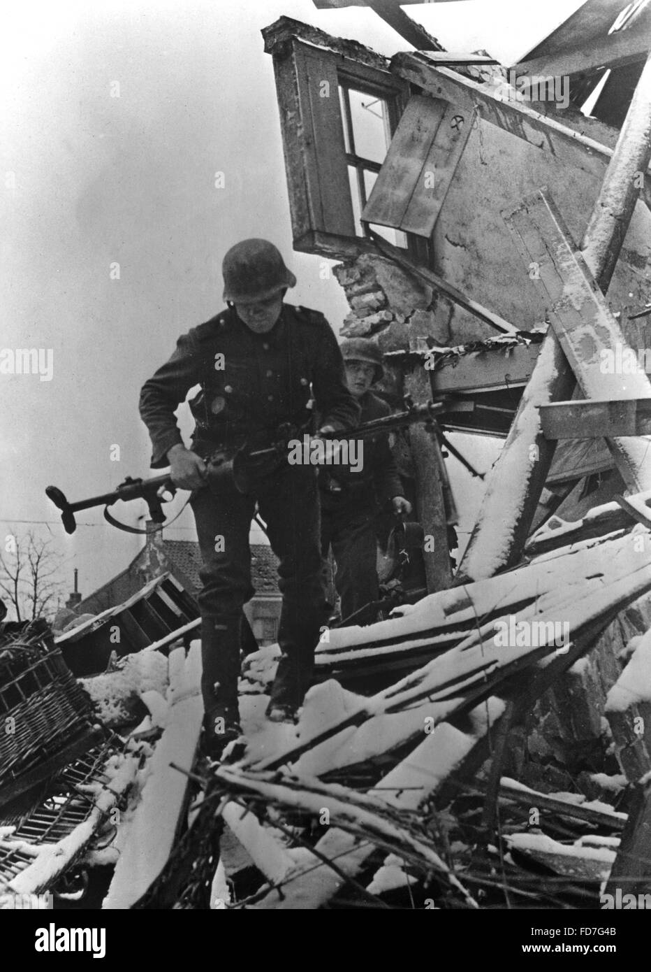 German soldiers with machine gun in front of the rubble of a house in ...