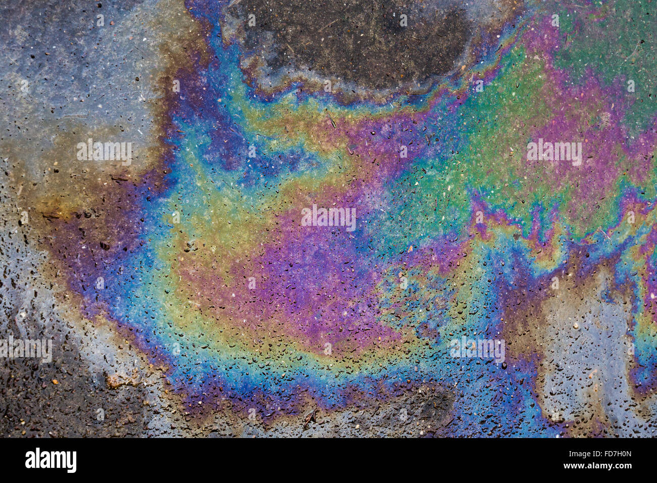 Rainbow colours in a film of oil on wet concrete Stock Photo - Alamy