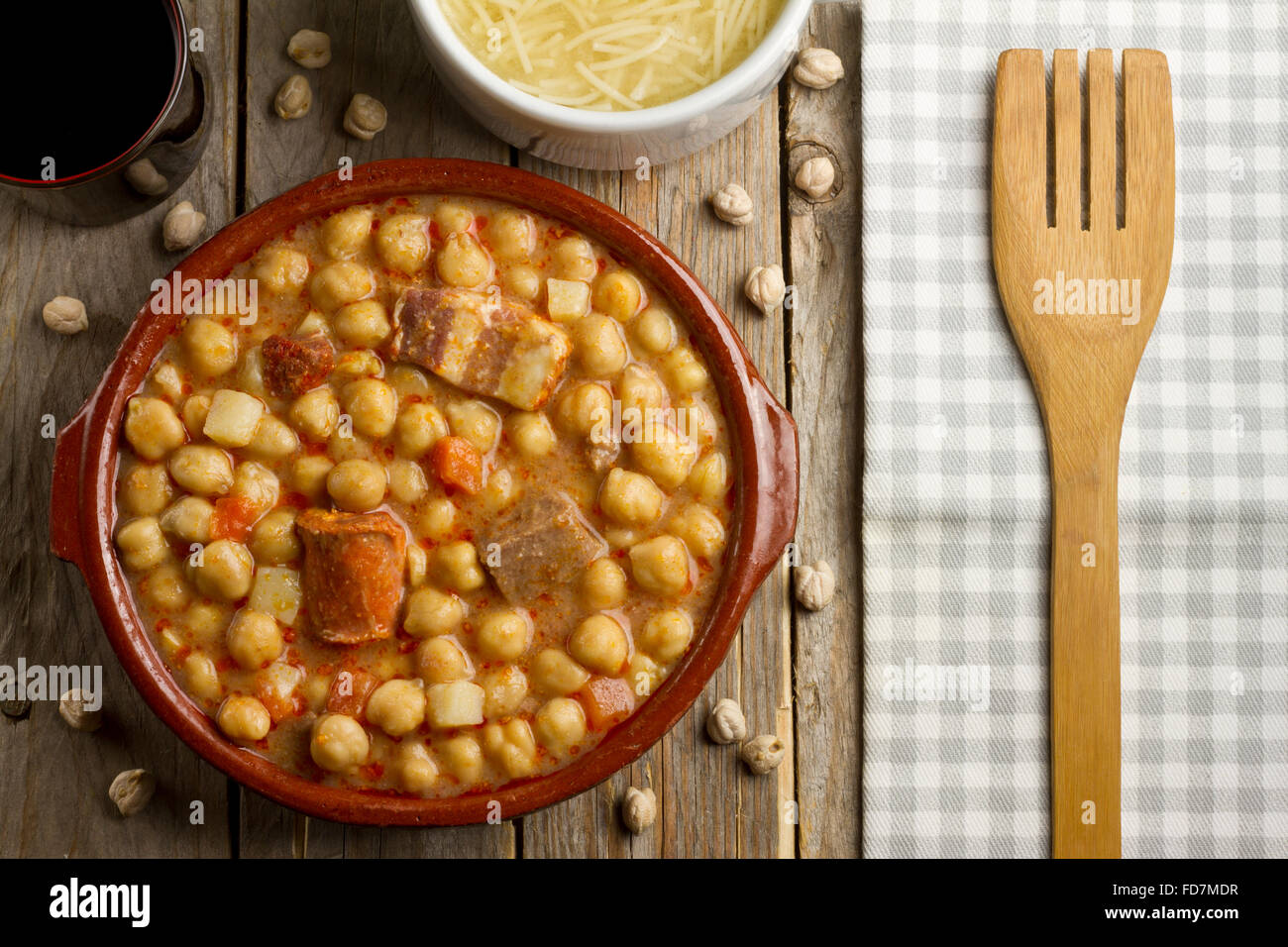 Spanish Cocido in an earthenware pot and a wooden fork on a white and ...