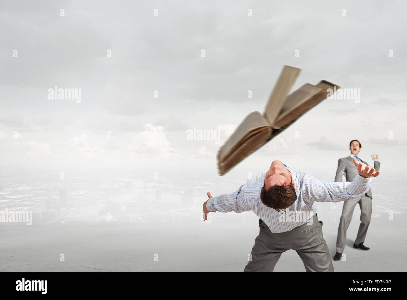Young businessman trying to evade from thrown book Stock Photo - Alamy