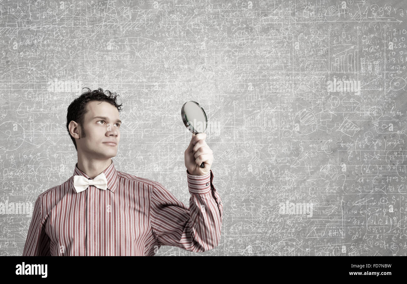 Funny image of young man looking in magnifying glass Stock Photo - Alamy