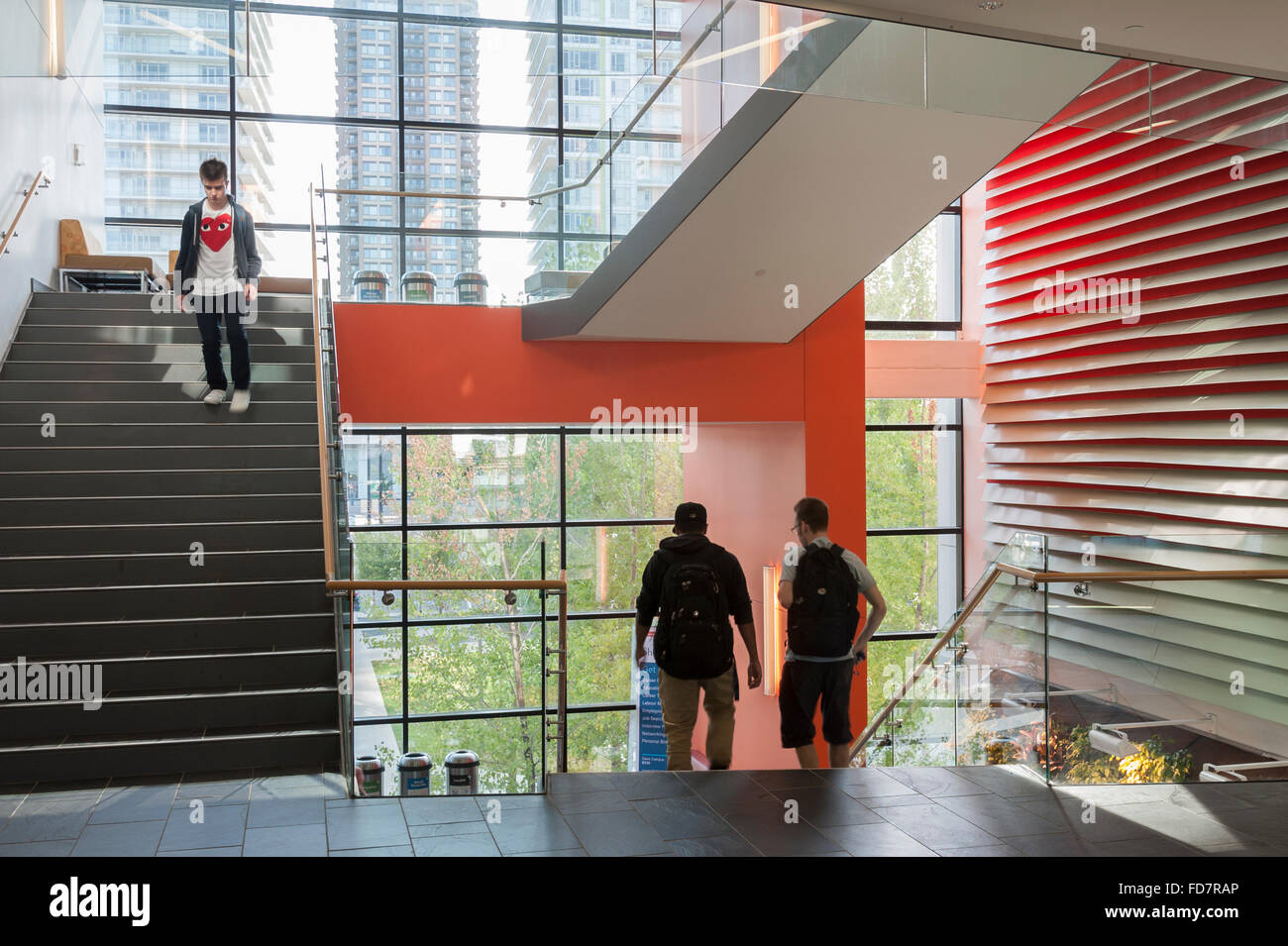 Students walking up and down stairs in a college campus checking smart ...