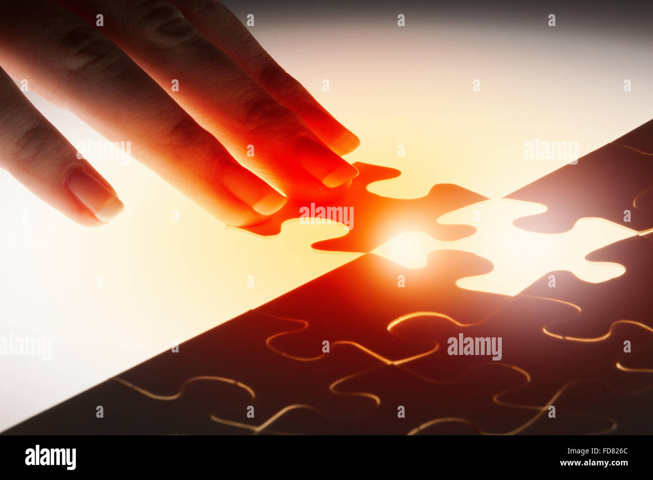 Close up of hands connecting puzzle element and making jigsaw complete ...