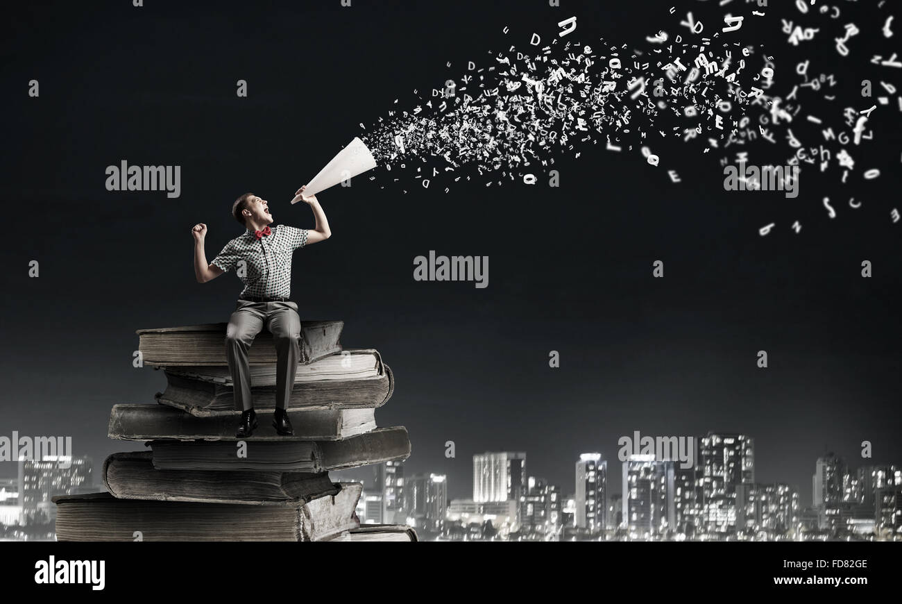 Young man in bow tie screaming in paper trumpet Stock Photo - Alamy