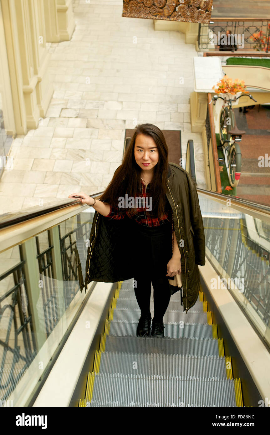 Girl on escalator going up in parka Stock Photo - Alamy