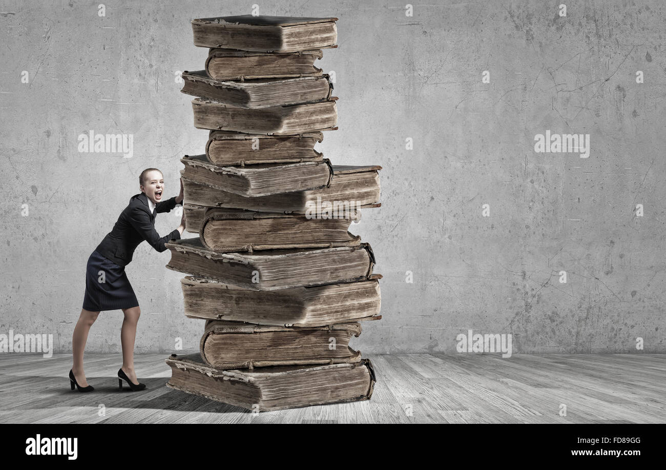 Young woman pushing huge pile of old books Stock Photo - Alamy