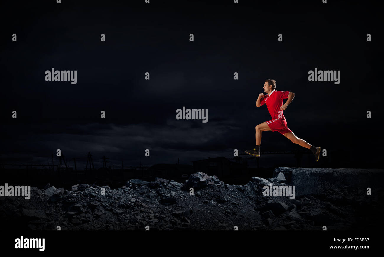 Running man in red sport wear on black background Stock Photo - Alamy
