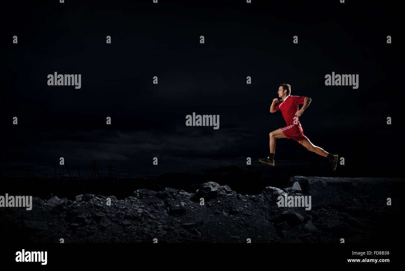 Running man in red sport wear on black background Stock Photo - Alamy