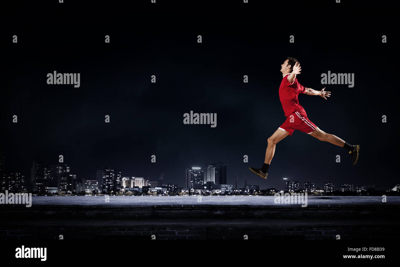 Running man in red sport wear on black background Stock Photo - Alamy