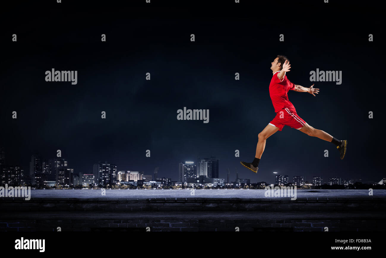 Running man in red sport wear on black background Stock Photo - Alamy