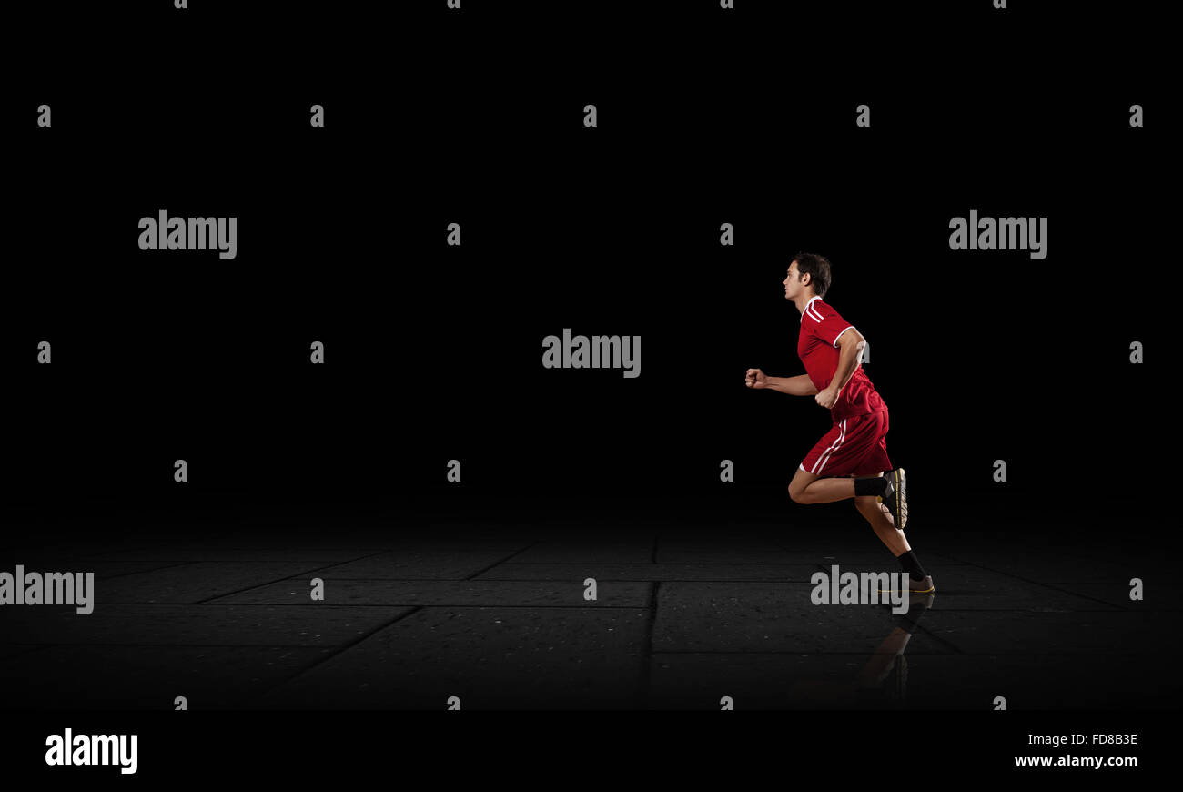 Running man in red sport wear on black background Stock Photo - Alamy