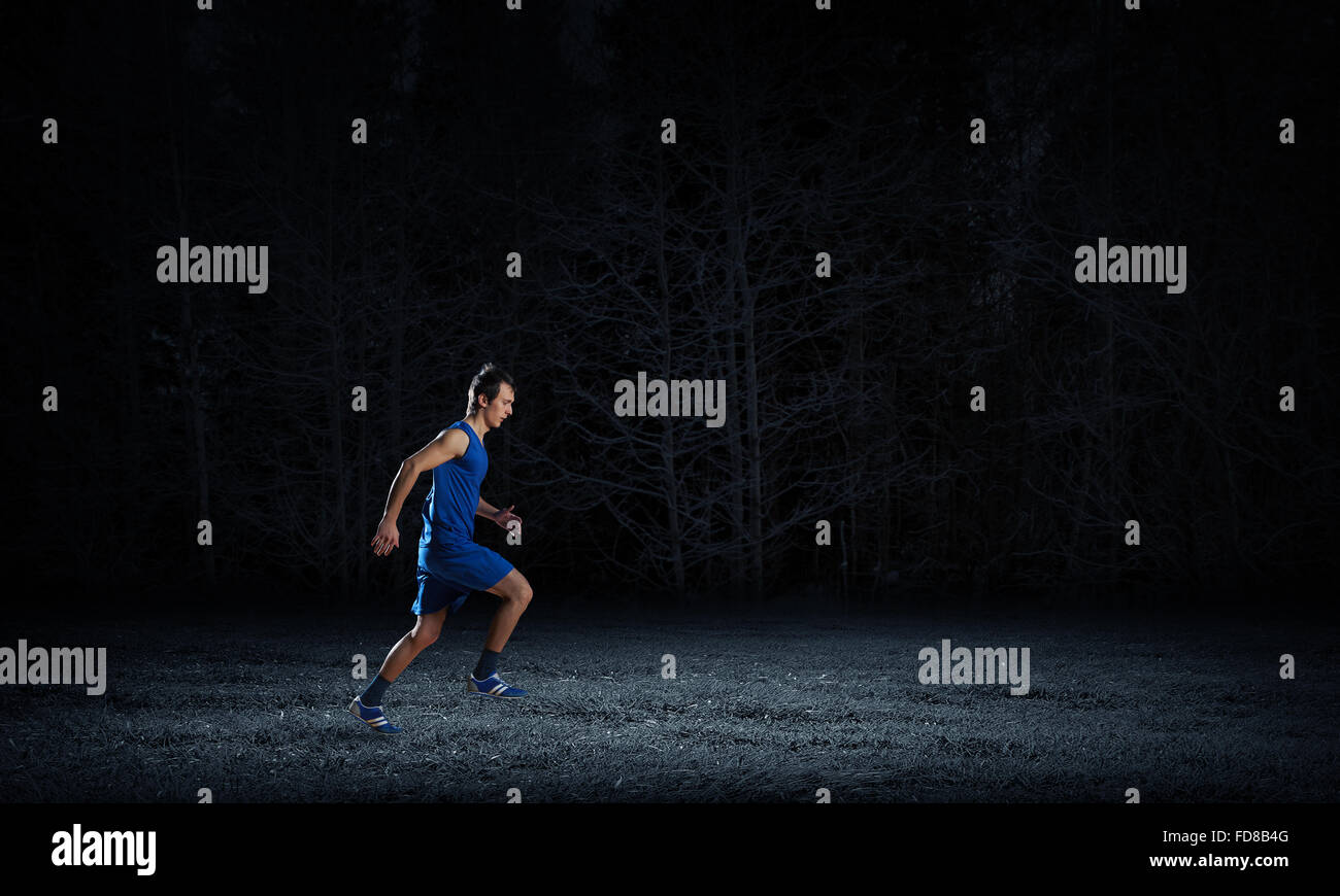 Running man in blue sport wear on black background Stock Photo - Alamy