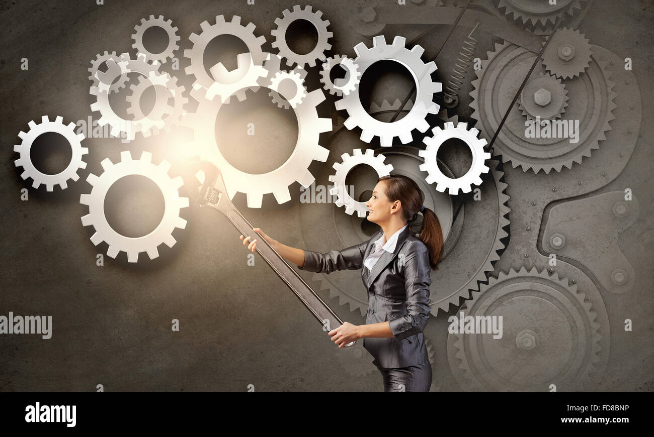 Young businesswoman fixing gears mechanism with wrench Stock Photo - Alamy