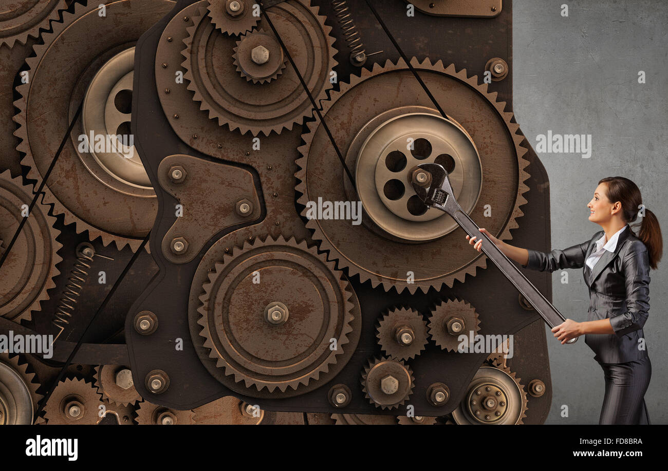 Young businesswoman fixing gears mechanism with wrench Stock Photo - Alamy