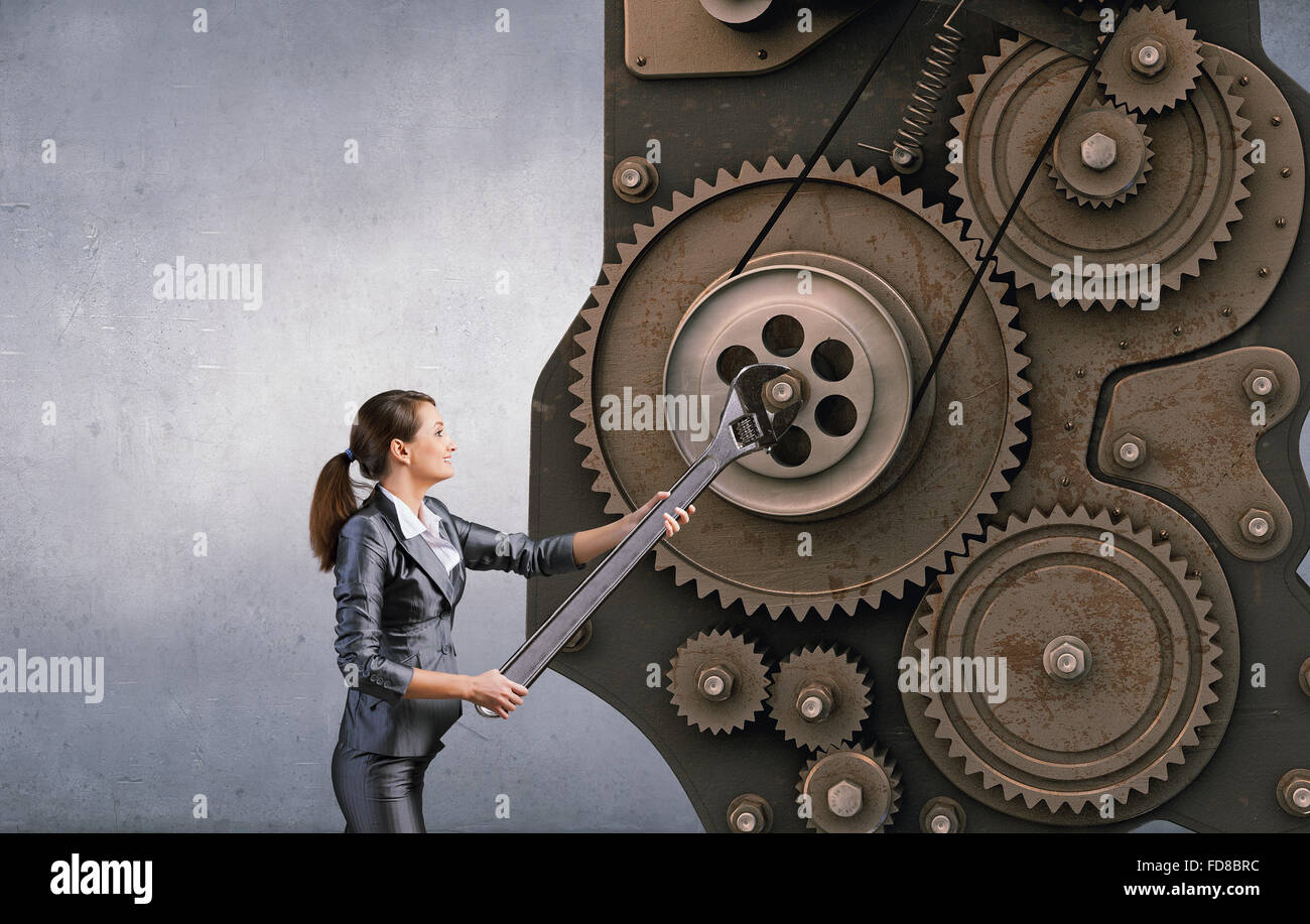 Young businesswoman fixing gears mechanism with wrench Stock Photo - Alamy