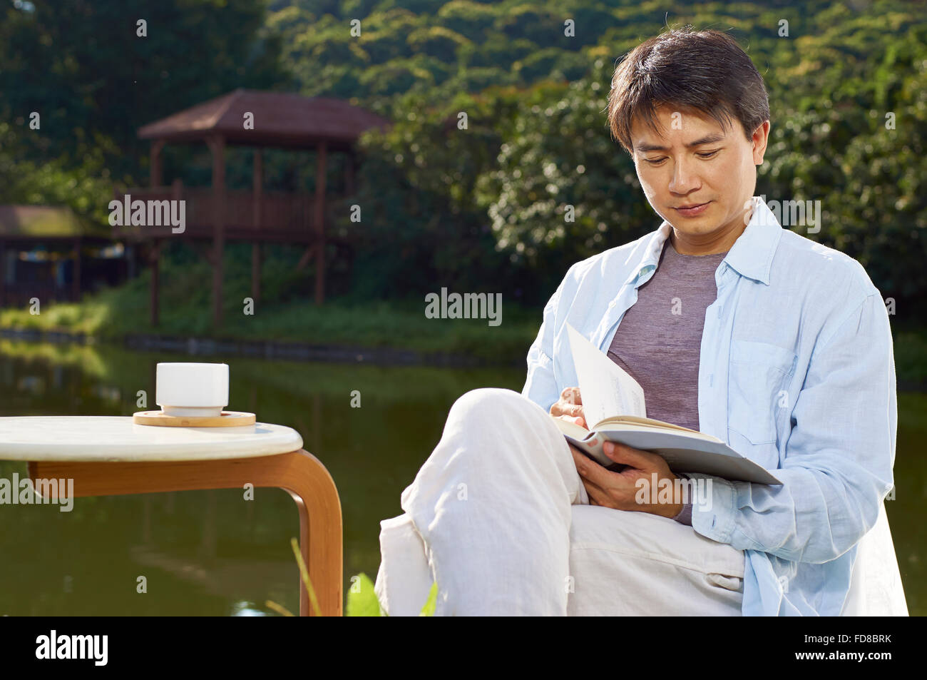 Chinese man reading waterside in morning Stock Photo - Alamy