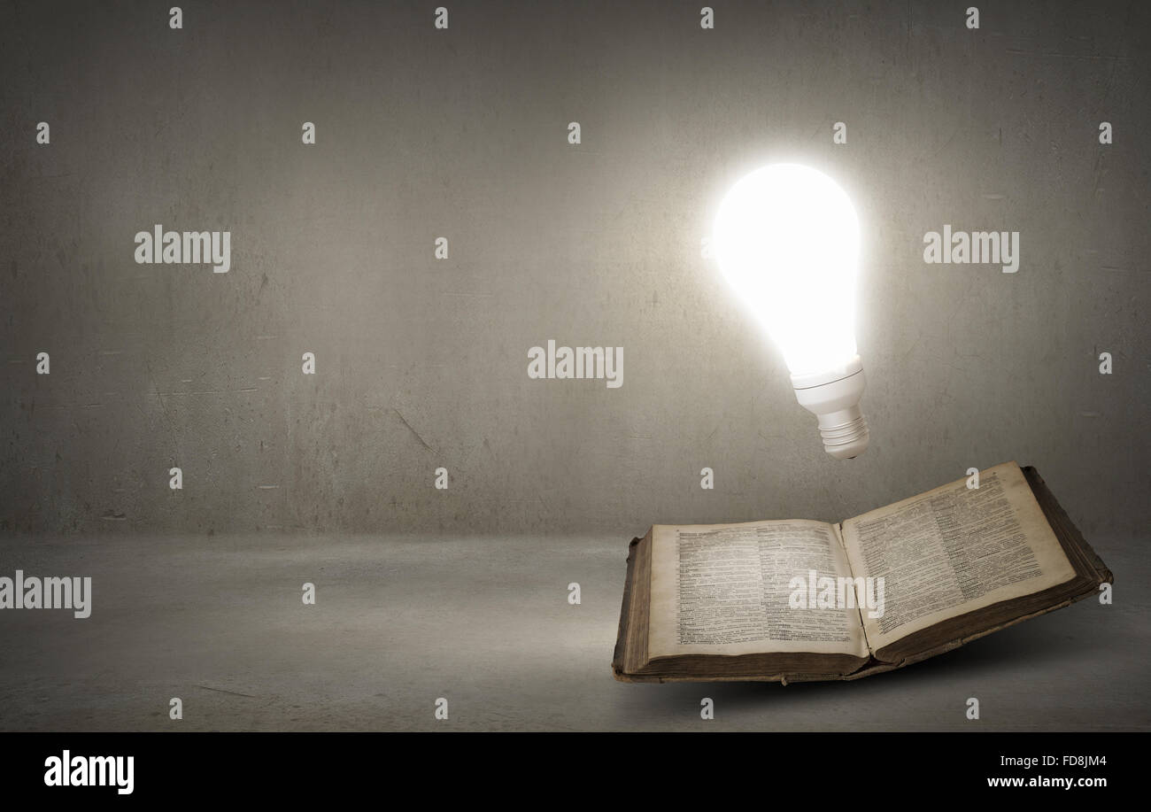 Old opened book and glowing light bulb Stock Photo - Alamy
