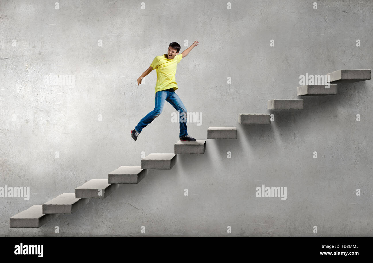 Young man walking up on staircase representing success concept Stock ...
