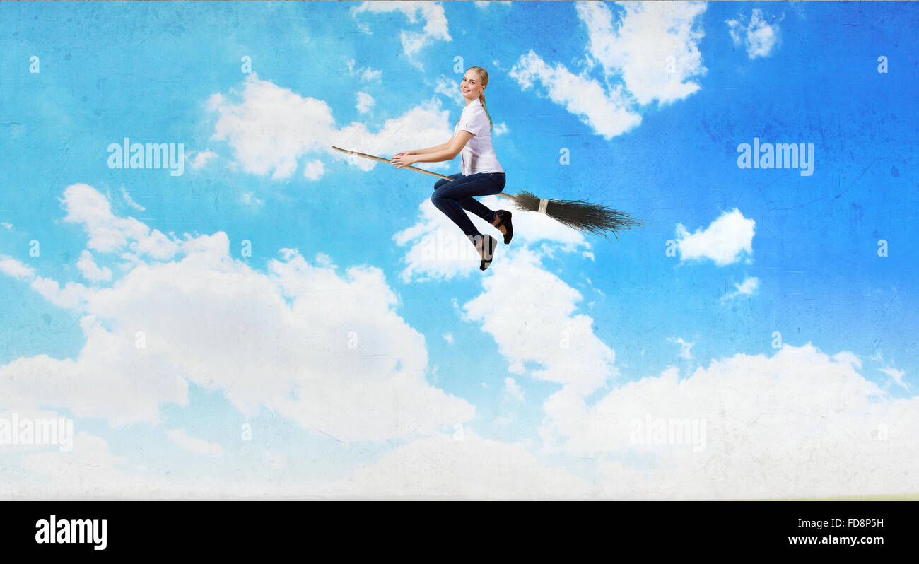 Happy young woman flying in sky on broom Stock Photo - Alamy
