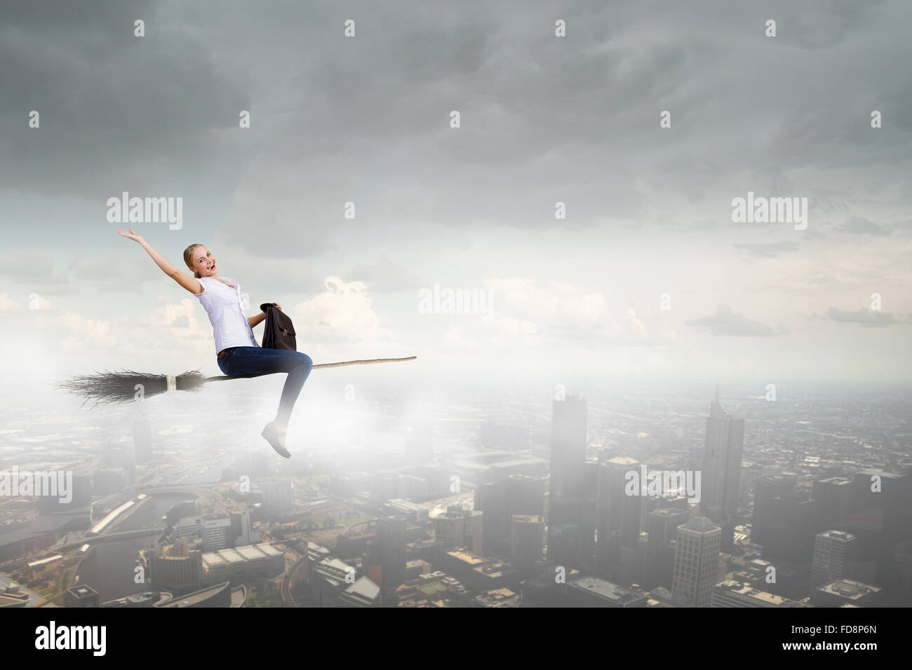 Happy young woman flying in sky on broom Stock Photo - Alamy
