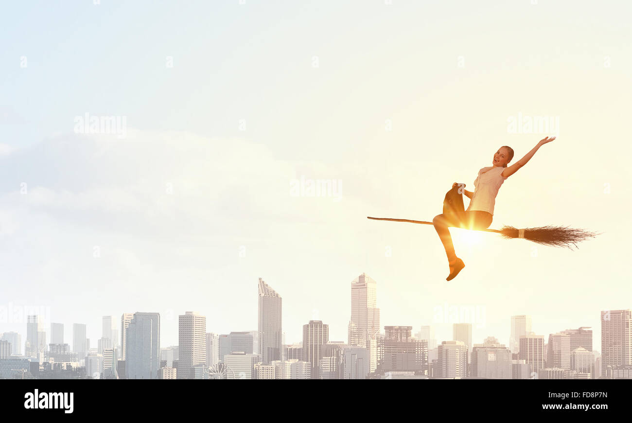 Happy young woman flying in sky on broom Stock Photo - Alamy