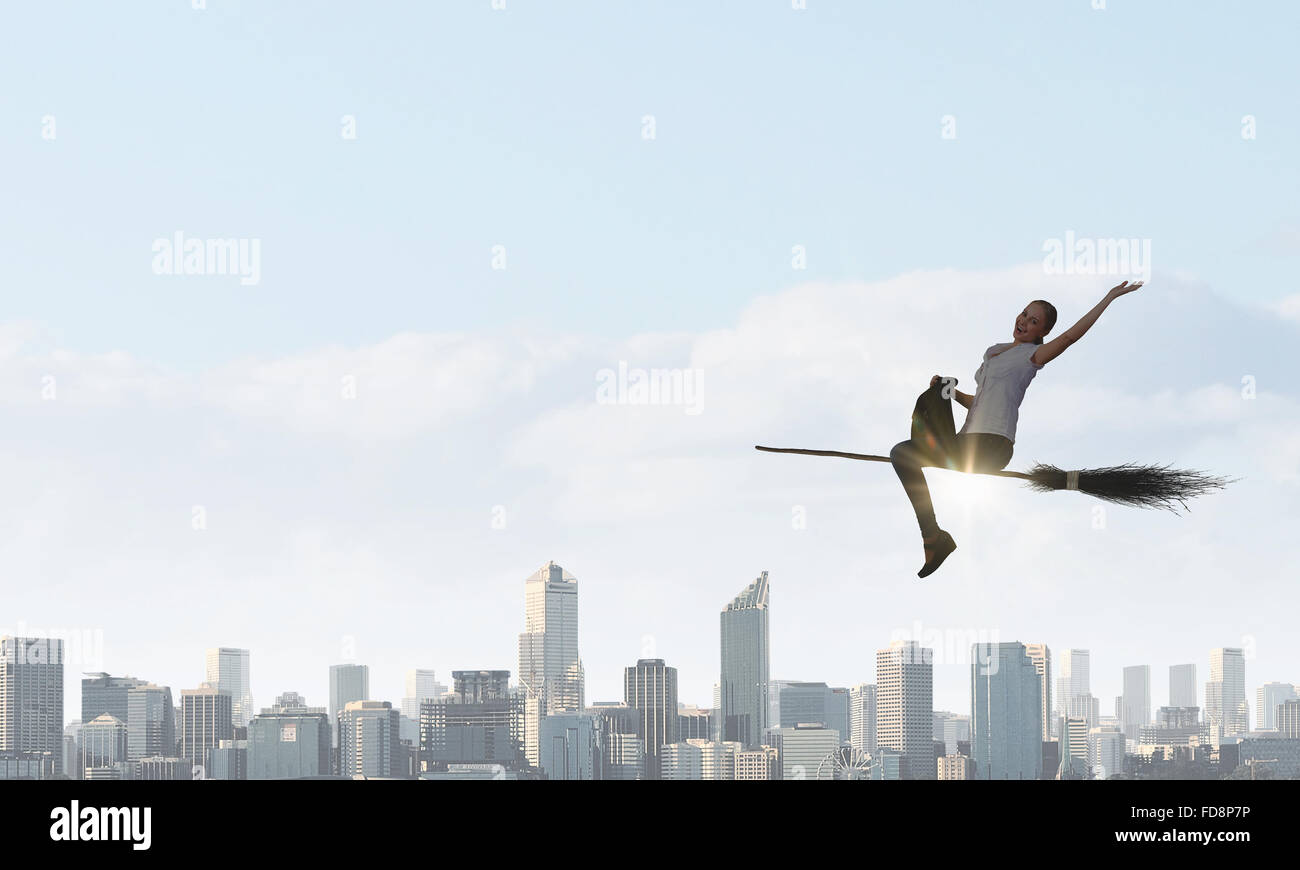 Happy young woman flying in sky on broom Stock Photo - Alamy