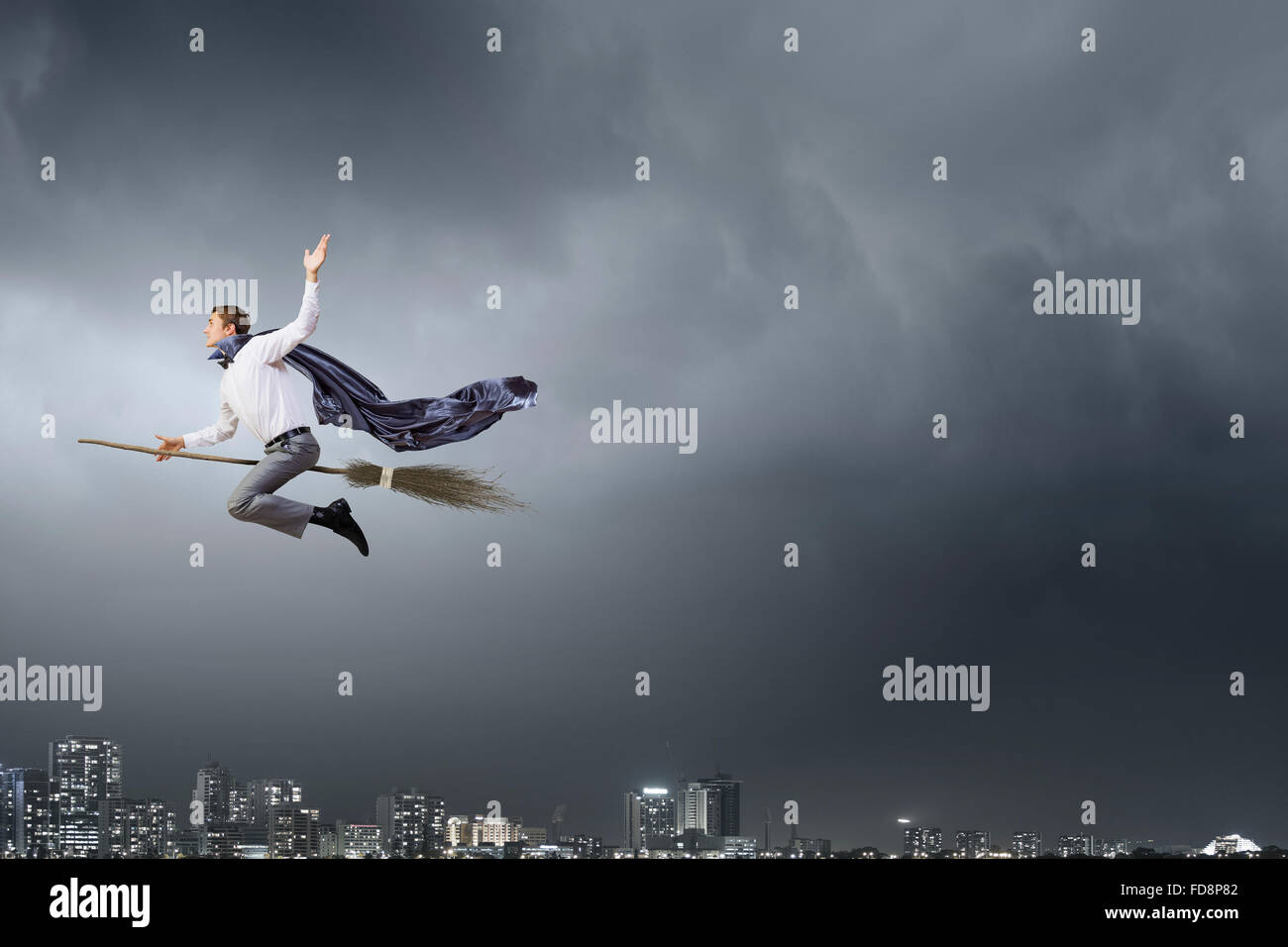 Young businessman flying on broom high in sky Stock Photo - Alamy