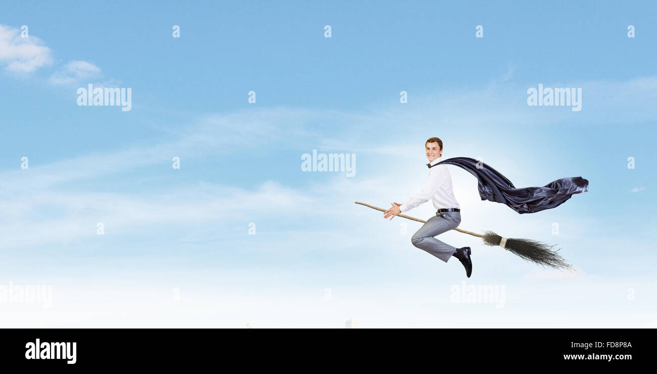 Young businessman flying on broom high in sky Stock Photo - Alamy