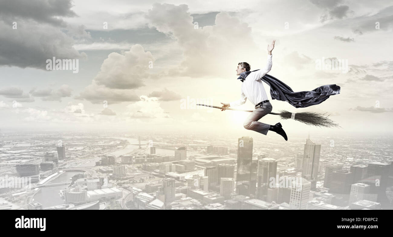 Young businessman flying on broom high in sky Stock Photo - Alamy